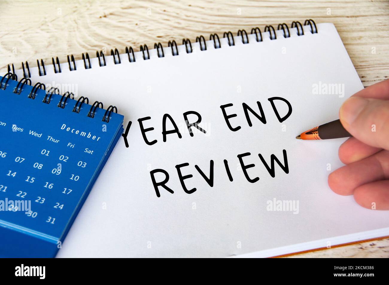 Year end review text on notepad with December calendar on wooden table ...