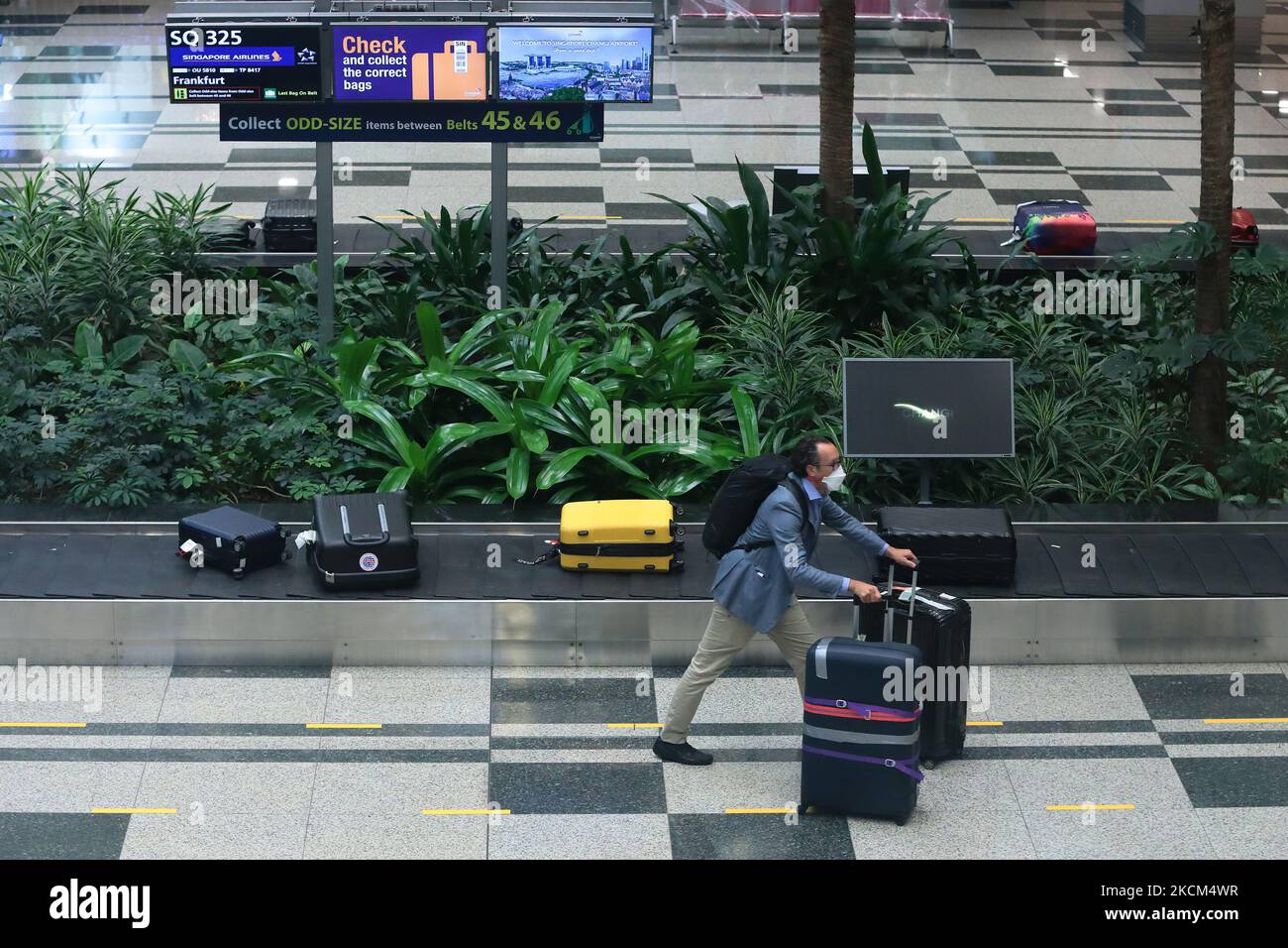 A male passenger wearing protective mask collects his bag after ...