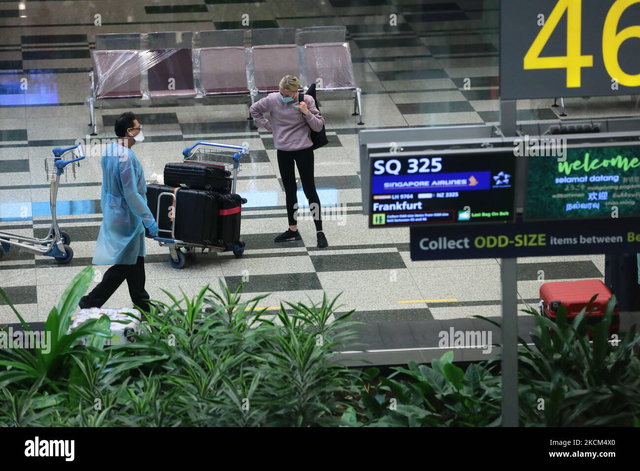 A female passenger wearing protective mask collects her bags after ...
