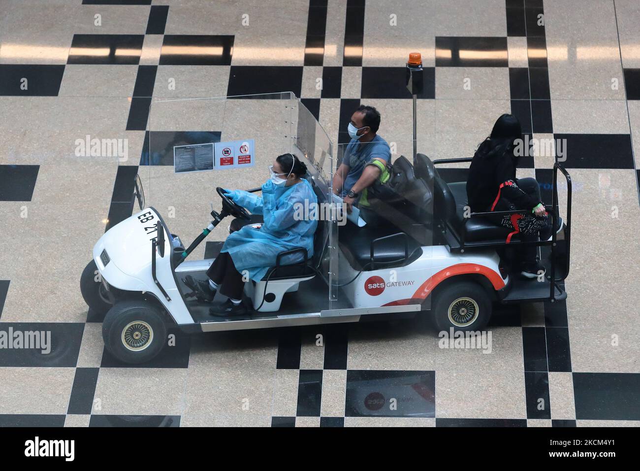 Travellers wearing protective mask ride on a buggy along the transit ...