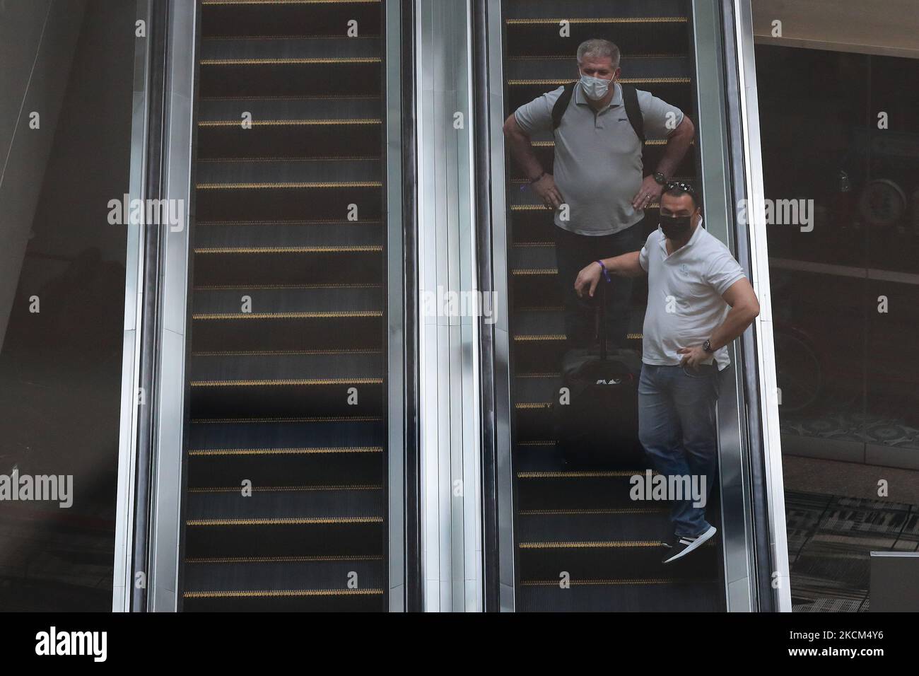 Travellers wearing protective mask take the escalator at Changi ...