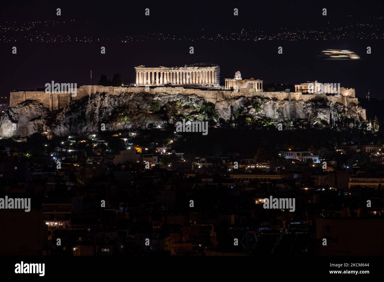 Night view of the Parthenon and Acropolis with a ferry boat passing in the background in the ...
