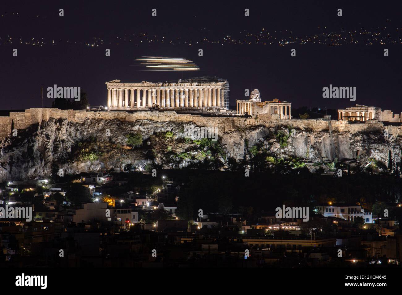 Night view of the Parthenon and Acropolis with a ferry boat passing in ...