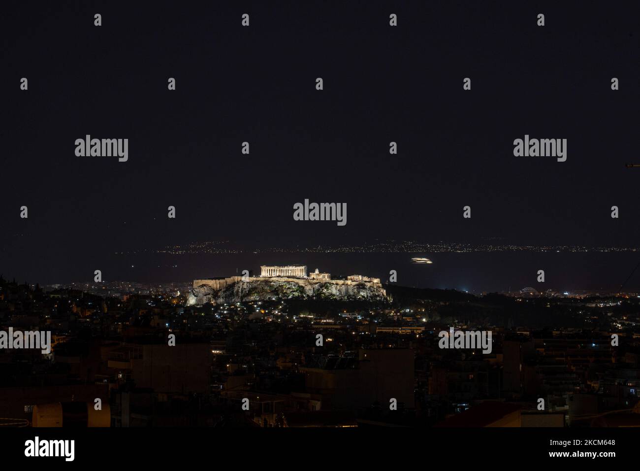 Night view of the Parthenon and Acropolis with a ferry boat passing in the background in the ...