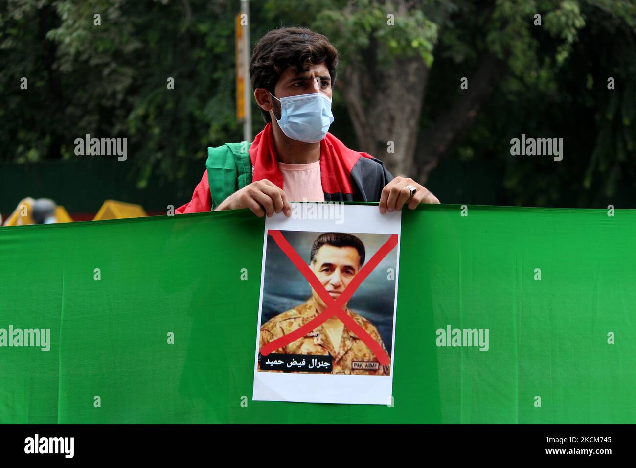 An Afghan national residing in India holds a poster of ISI chief Faiz ...