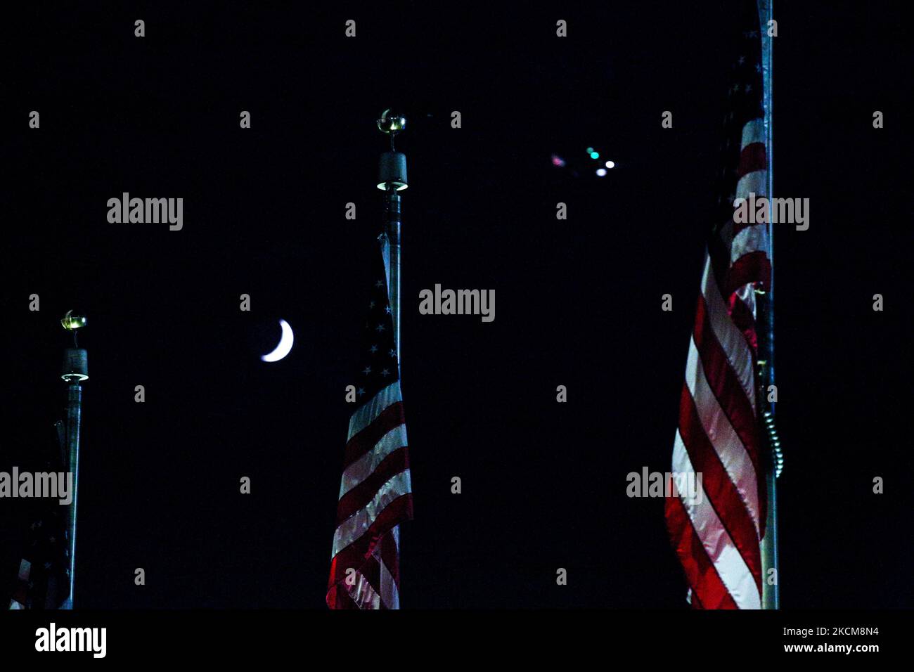 An airplane flies past a crescent moon and the Washington Monument on ...