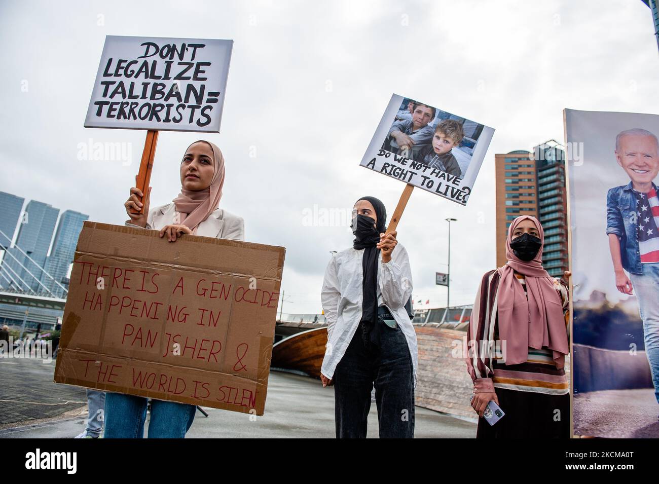 Three Afghan women wearing hijabs are holding placards in support of ...