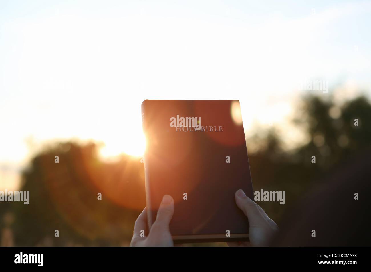 A Christian praying with the bright sunlight and the setting sun and ...