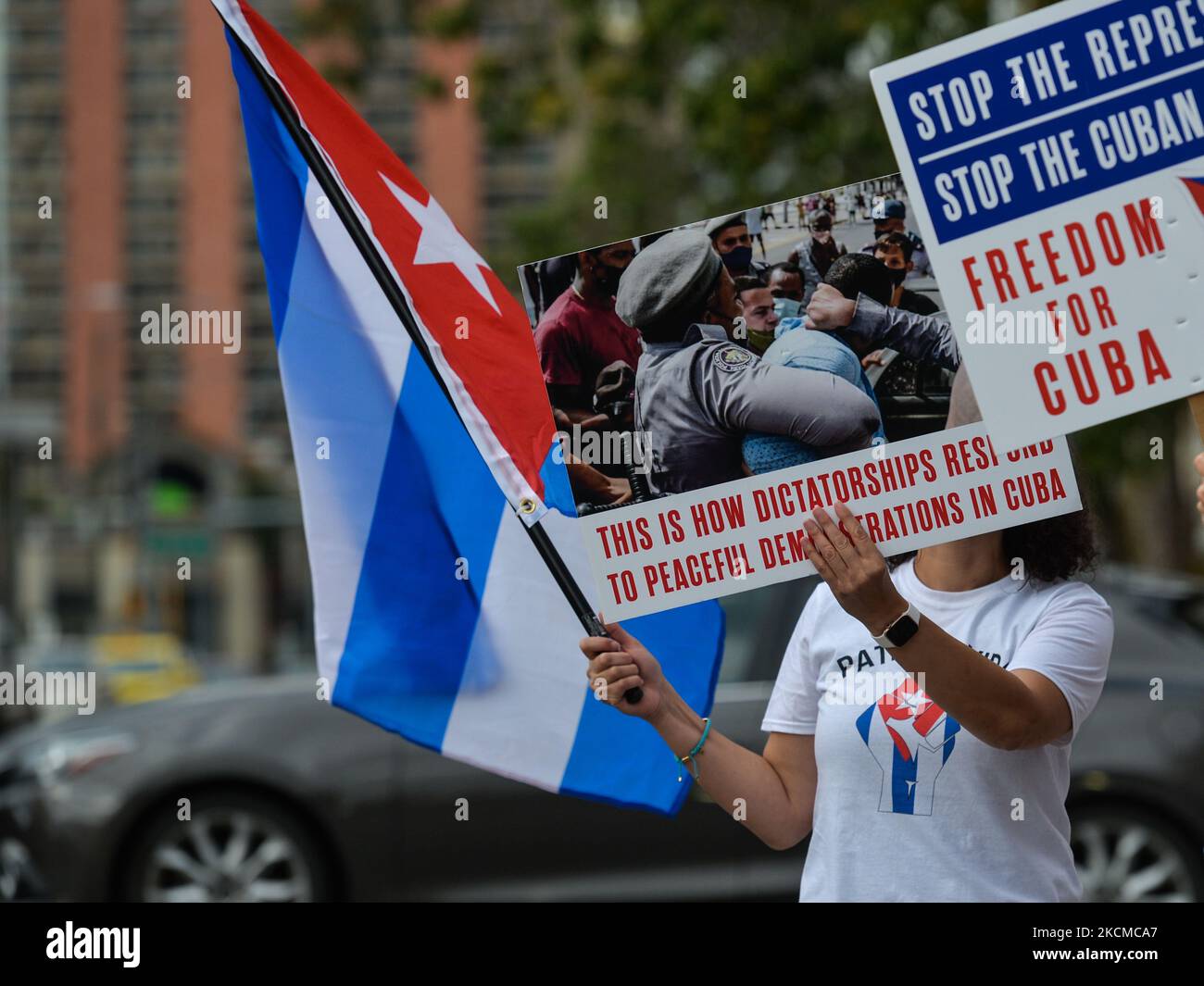 A protester seen with Cuban national flag and an image with words 'This ...