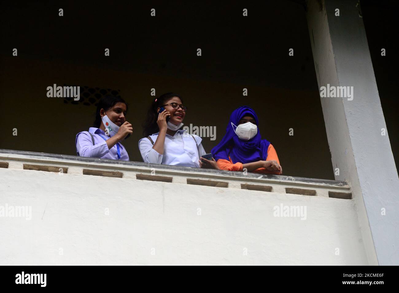 Students wearing face masks look out from the balconies of the school ...