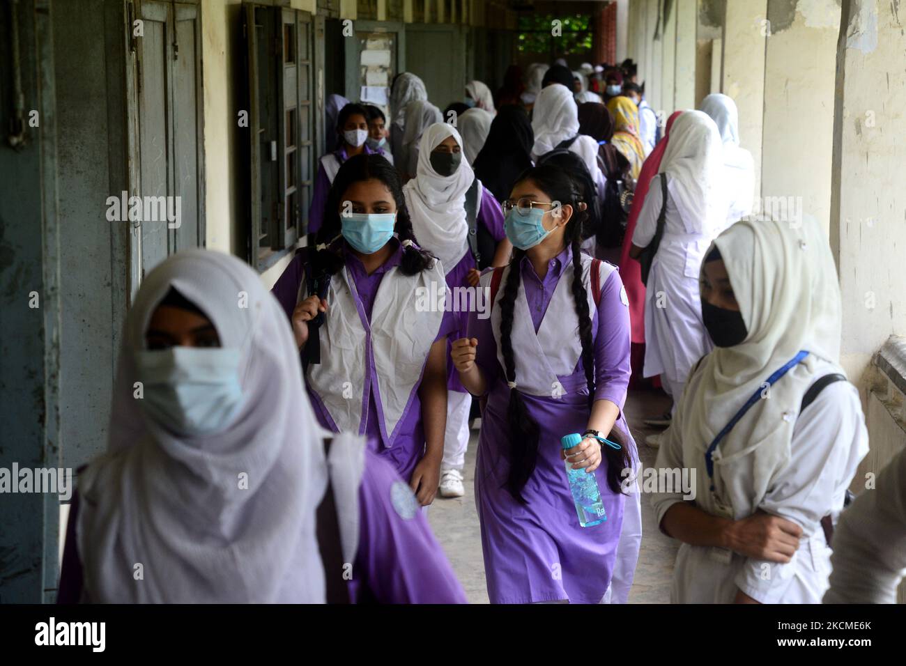 Students wearing face masks look out from the balconies of the school ...