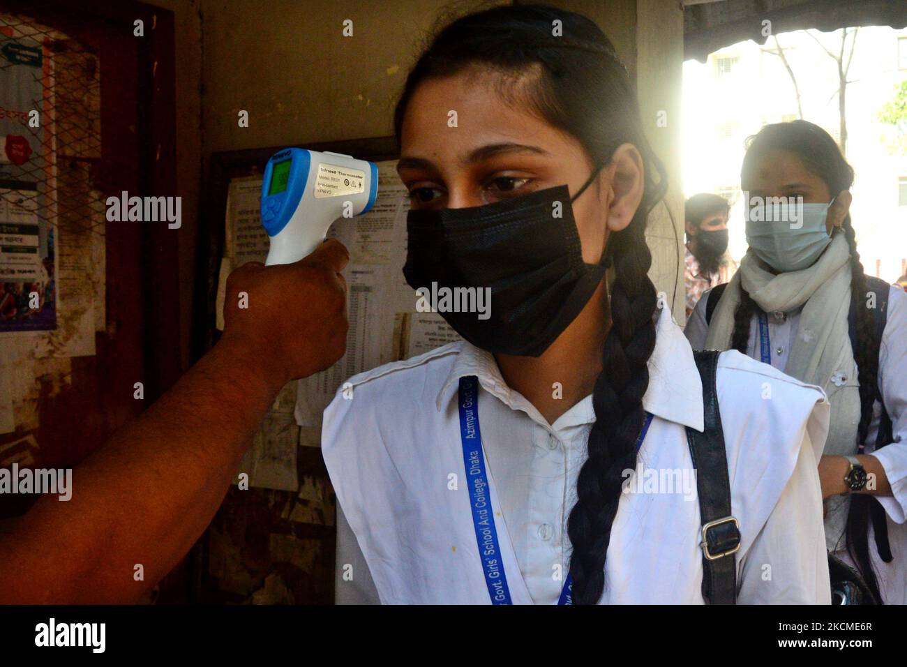 An official checks the body temperature of a student upon her arrival ...