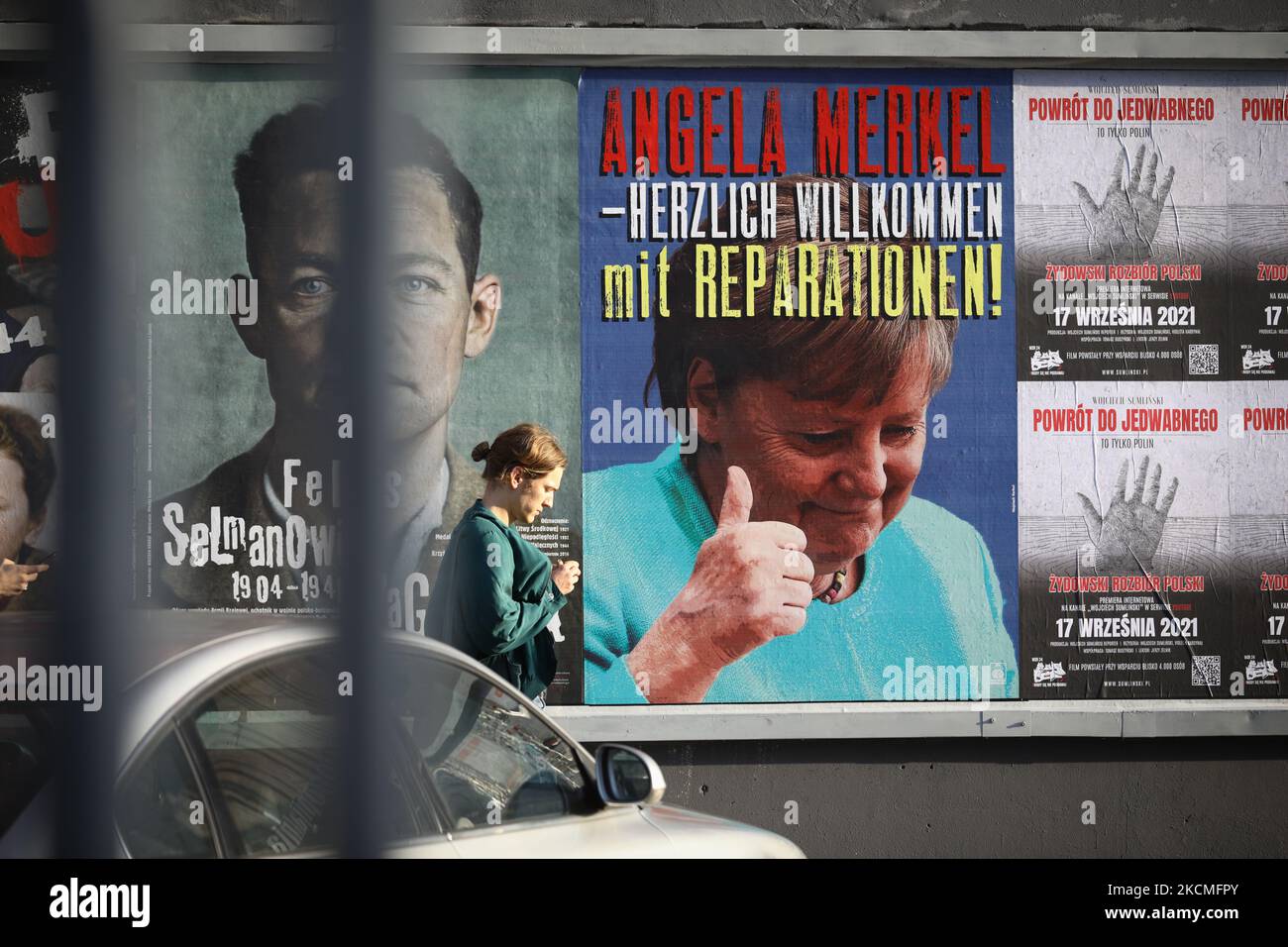 A woman walks past a poster with a picture of German Chancellor Angela ...