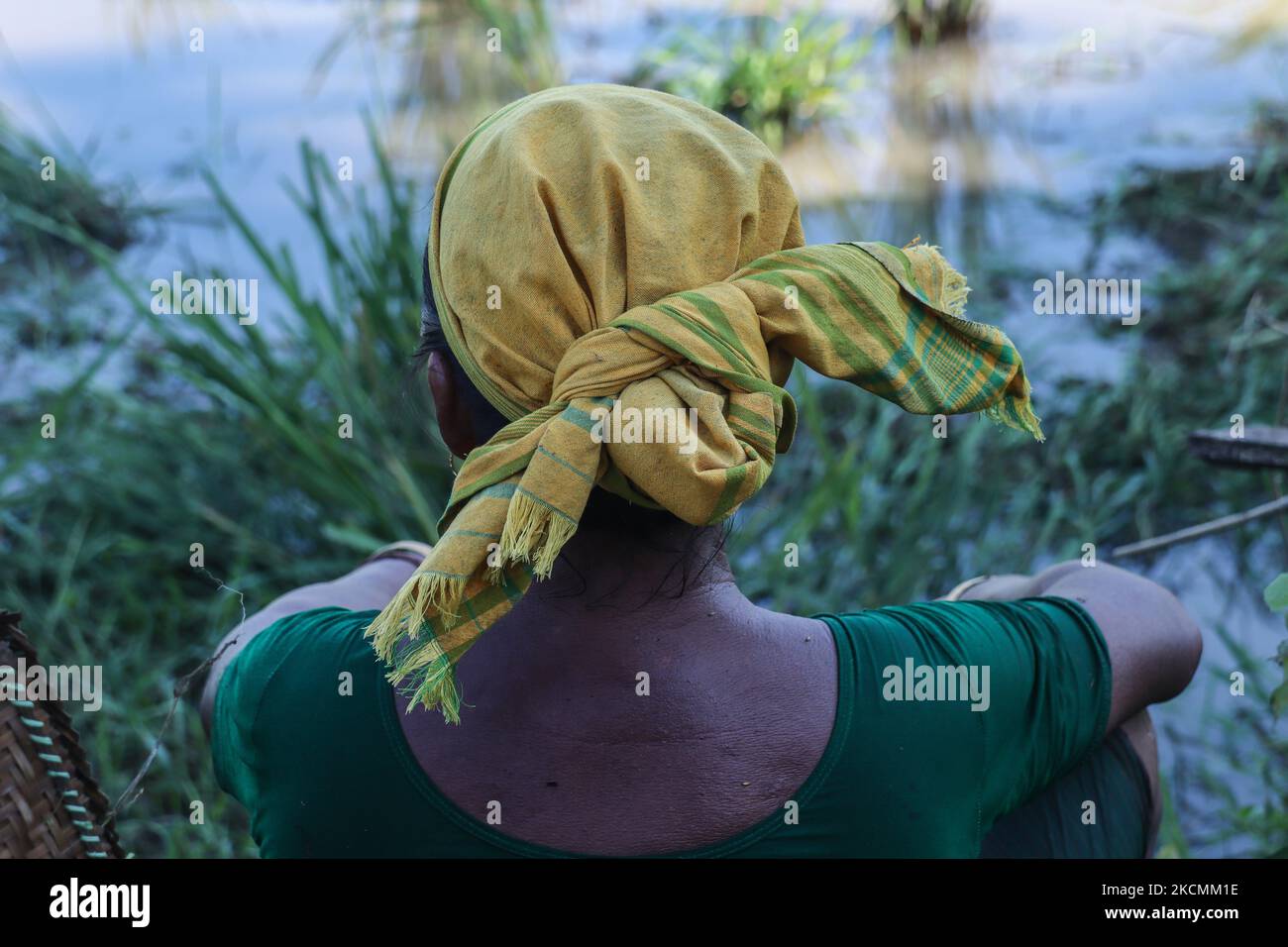 Bodo community woman takes rest during fishing at a mud water field, at ...