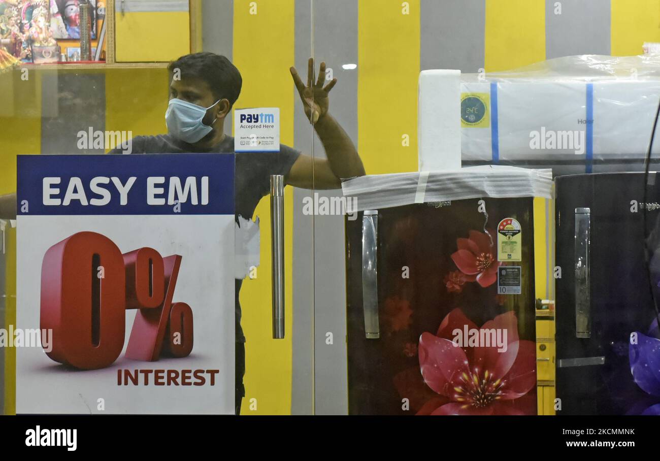 A man stands in front of an electronic showroom where a Paytm payment ...