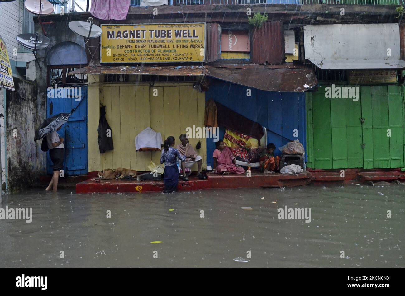 Homeless people take shelter on a side of a flooded street due to heavy ...