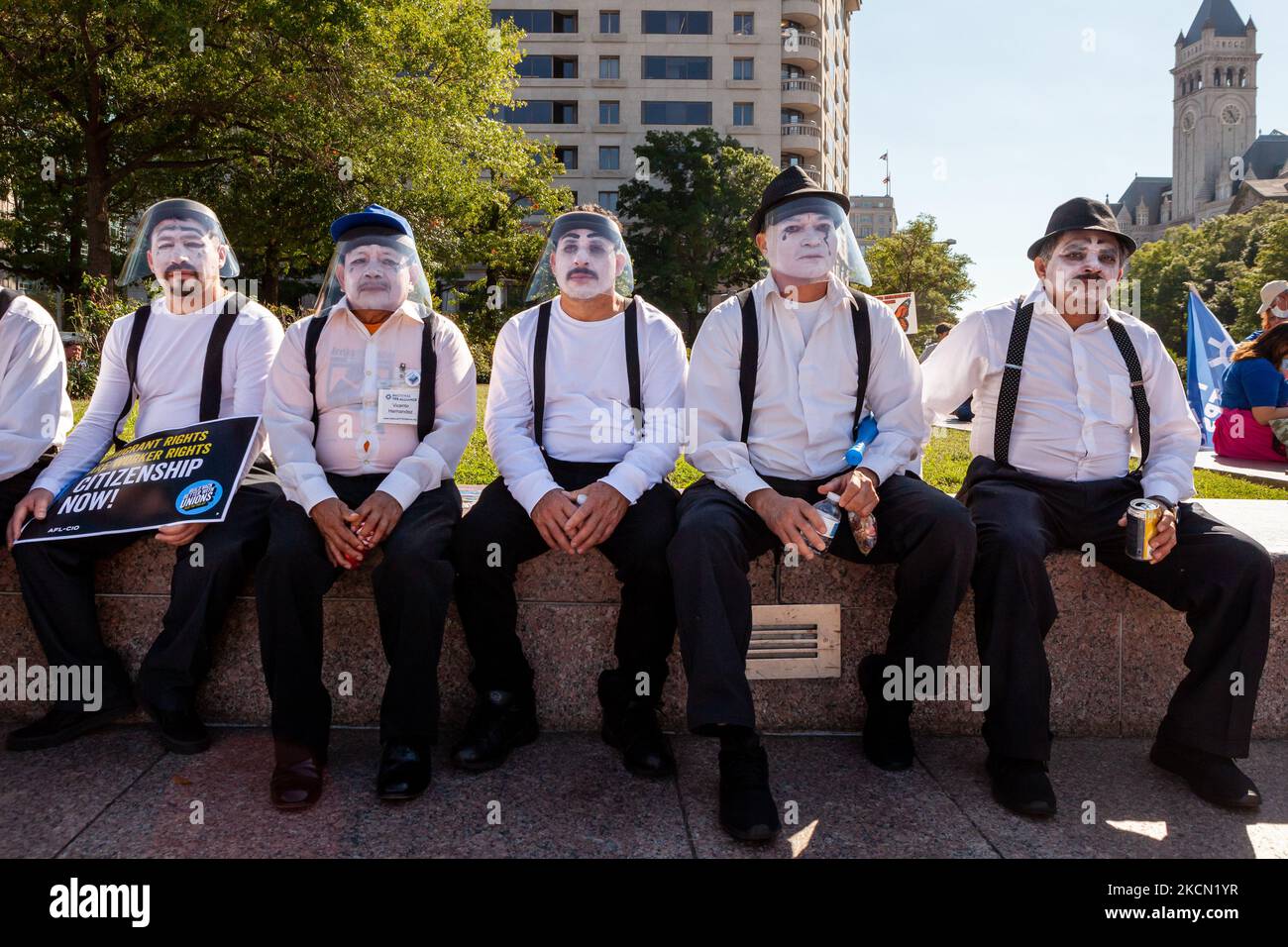 A group of men dressed as mimes await the beginning of a march for ...