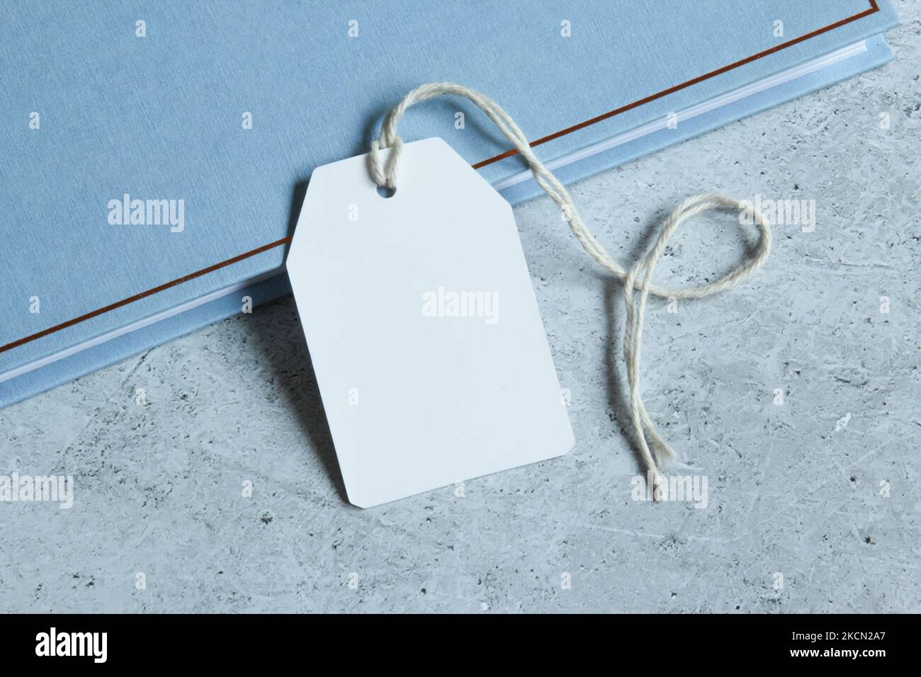 Rectangle white gift tag mockup with white card on blue book and grey ...