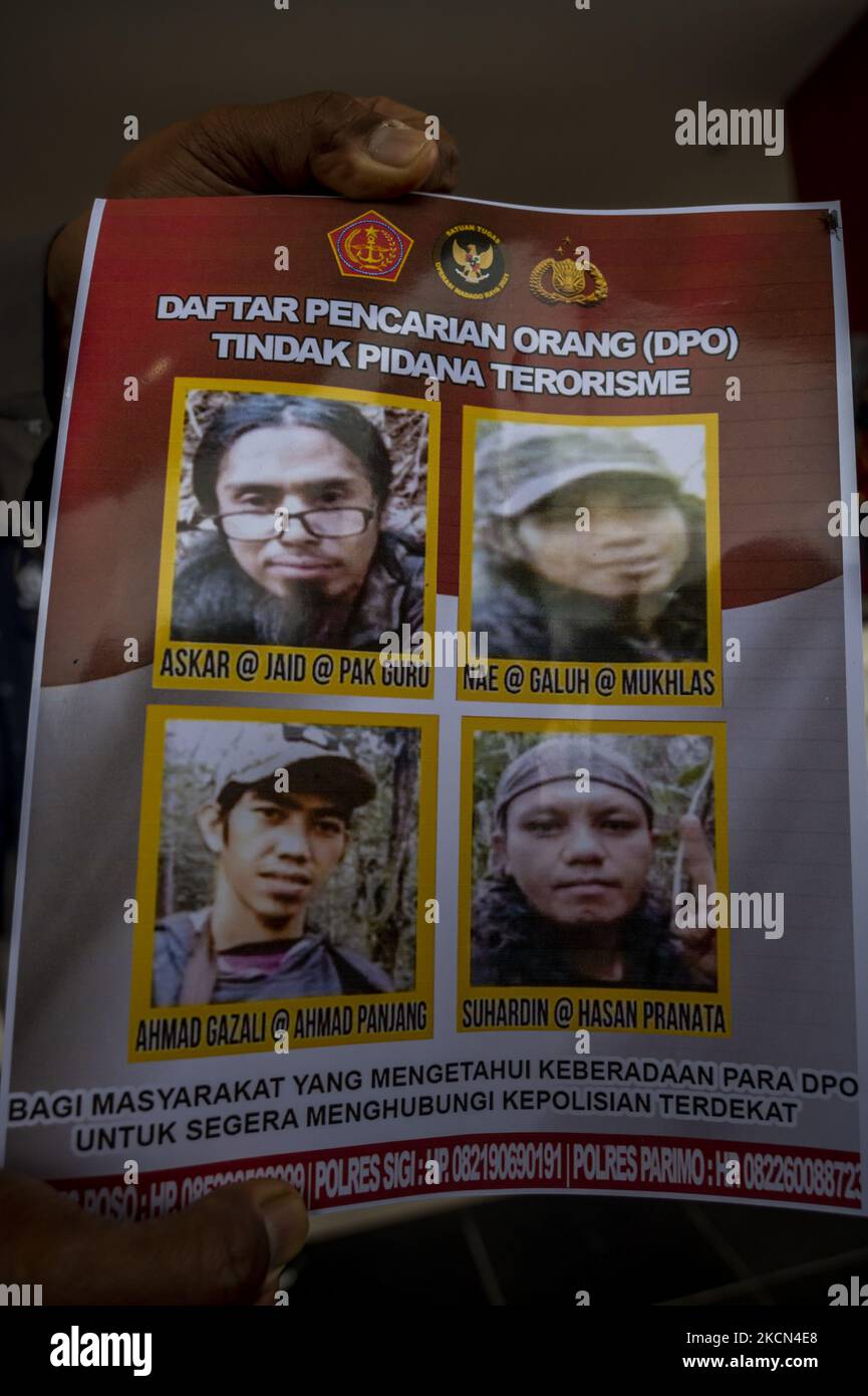 A police officer shows photos of the remaining four members of the Poso ...