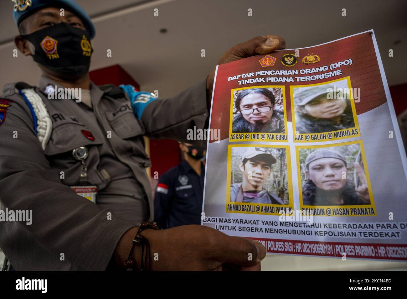 A police officer shows photos of the remaining four members of the Poso ...