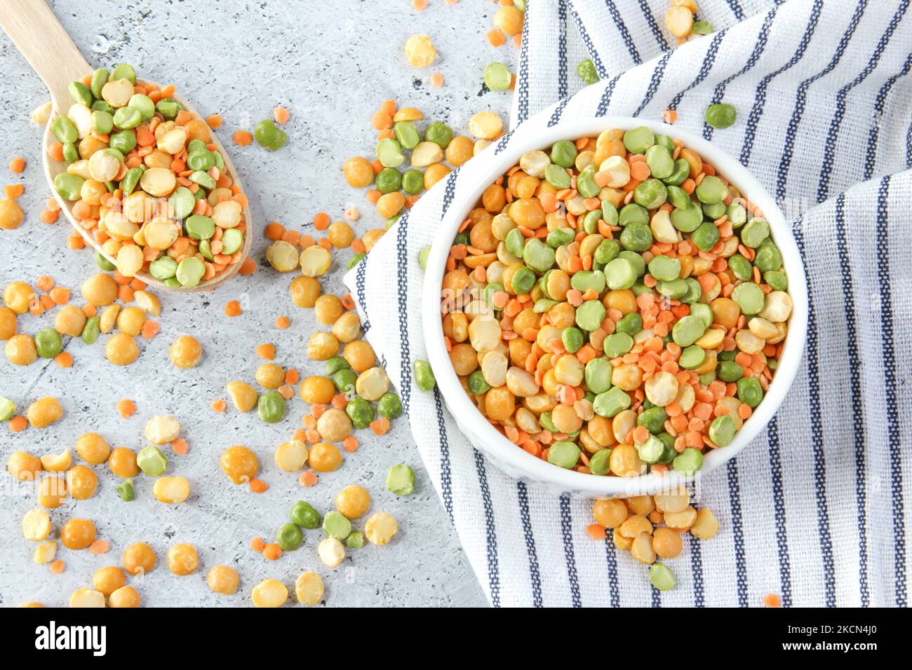 Different types of peas yellow and green in white bowl on grey stone ...