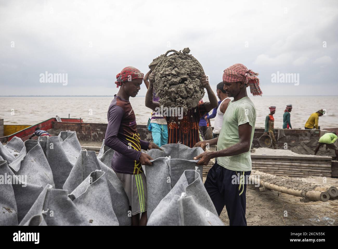 Workers prepare sandbags to repair the embankment designed to protect ...