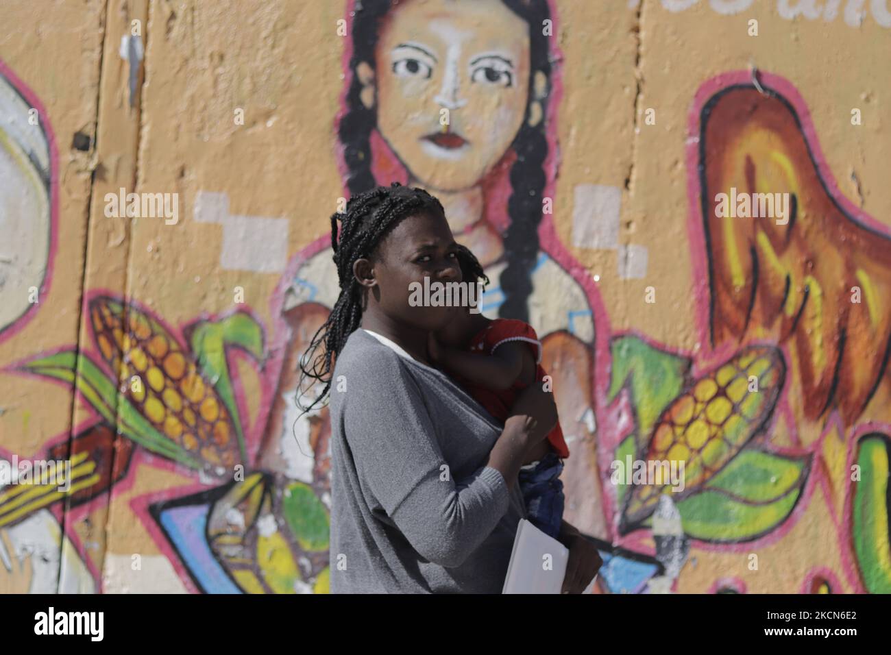 A haitian migrant carries her daughter as she walks through the streets ...
