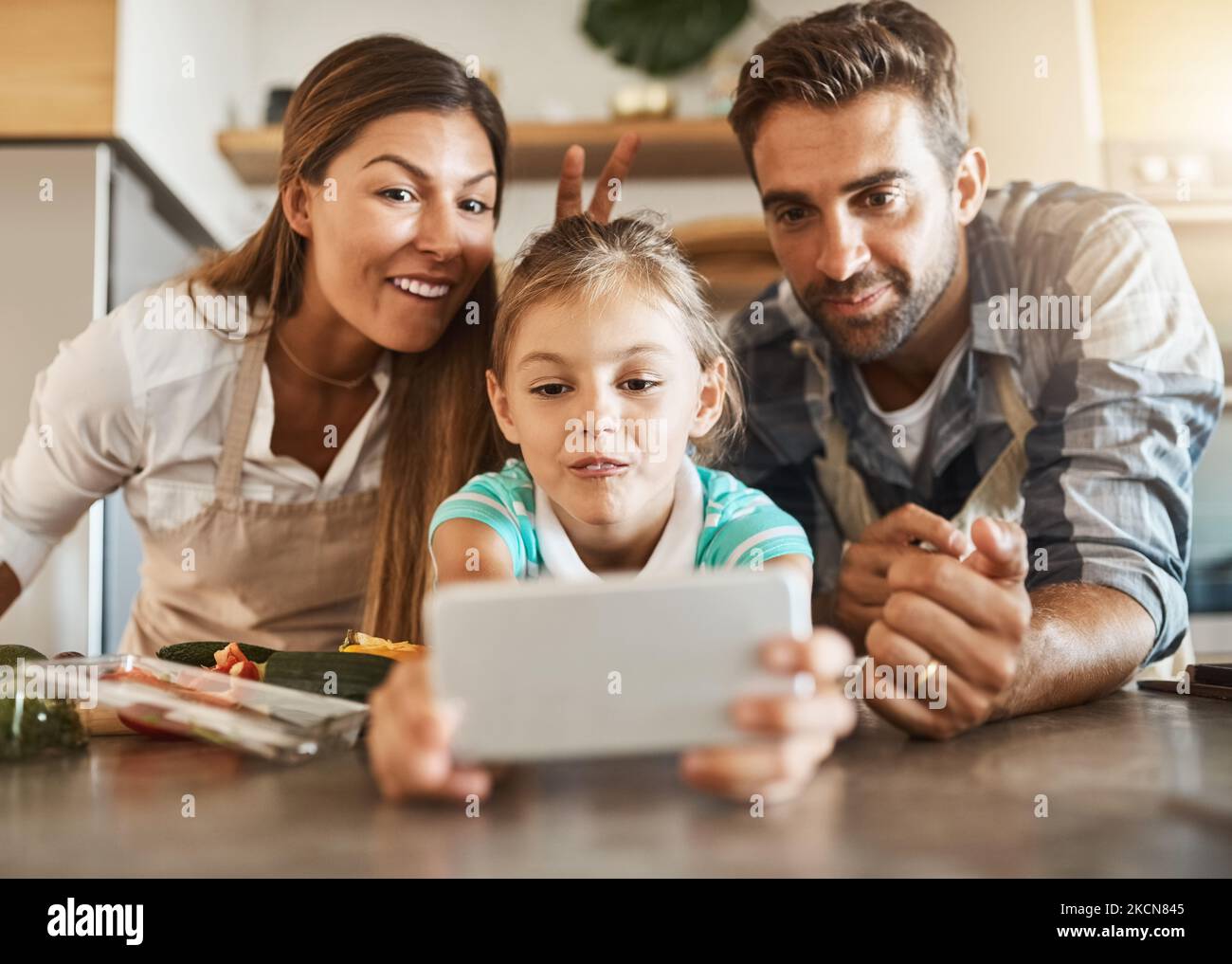 Documenting their kitchen adventures. a happy young family posing for a ...