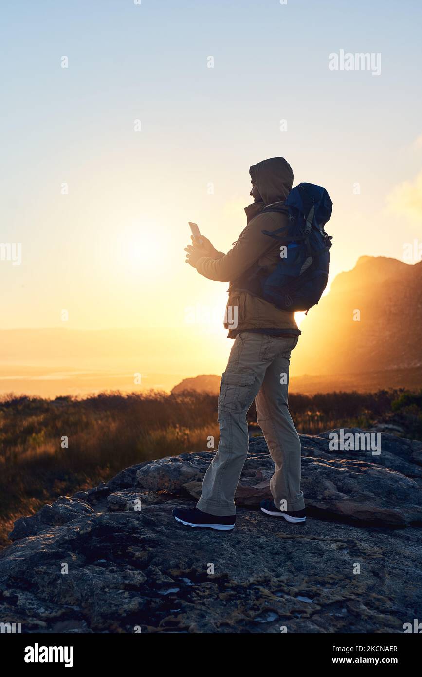 Connect with nature. a hiker taking a photo with his cameraphone on top ...