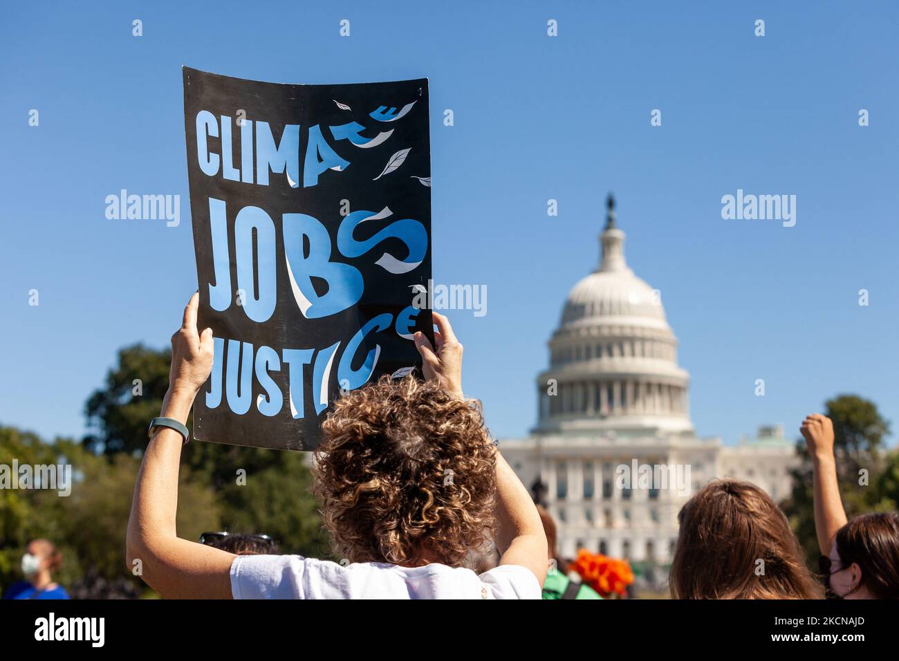A protester raises a sign that depicts the future being taken away from ...