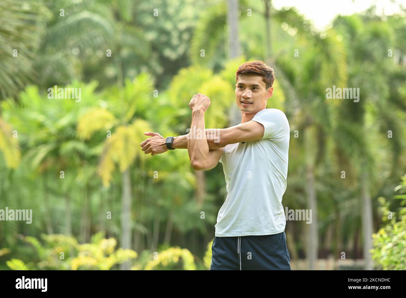 Handsome sportsman stretching muscle before workout session at the park ...