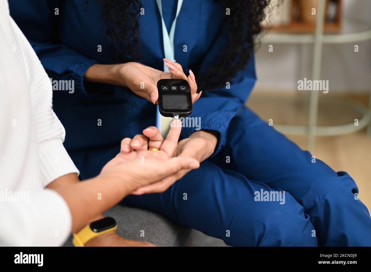 Nurse checking blood glucose levels of senior diabetic woman during a ...