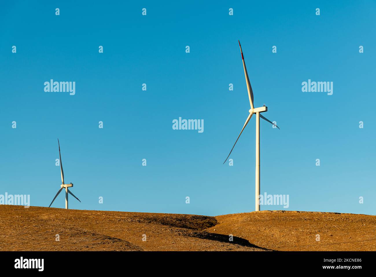 Multiple wind turbines standing on a hill at sunrise and generating ...