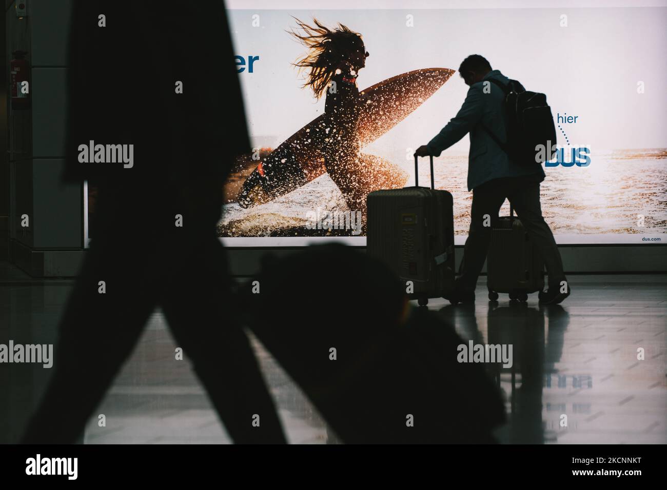 two travellers walk pass a big duesseldorf airport advertising sign at ...