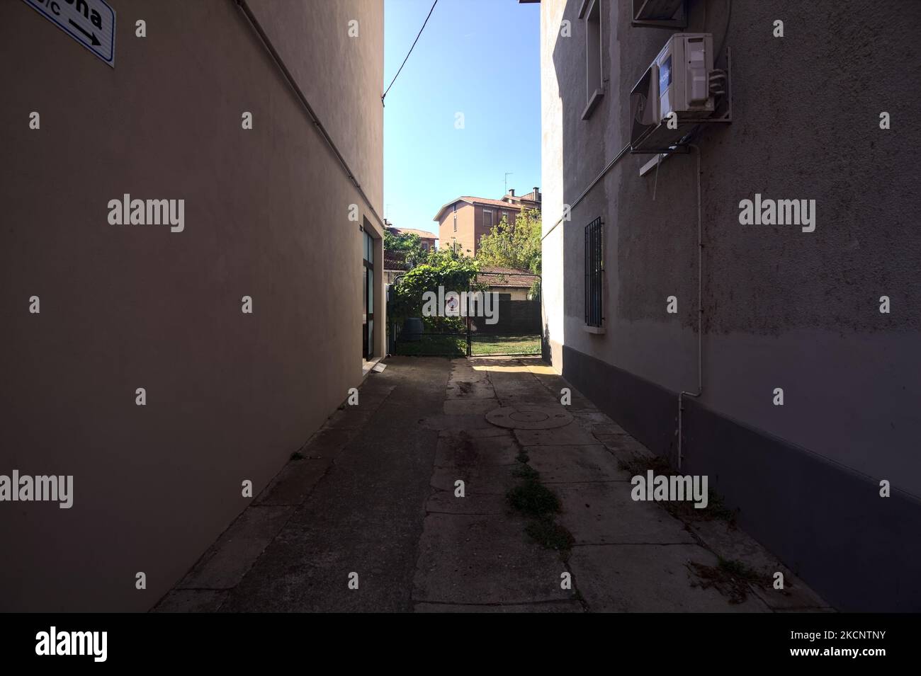 Narrow alley in the shade blocked by a gate Stock Photo - Alamy