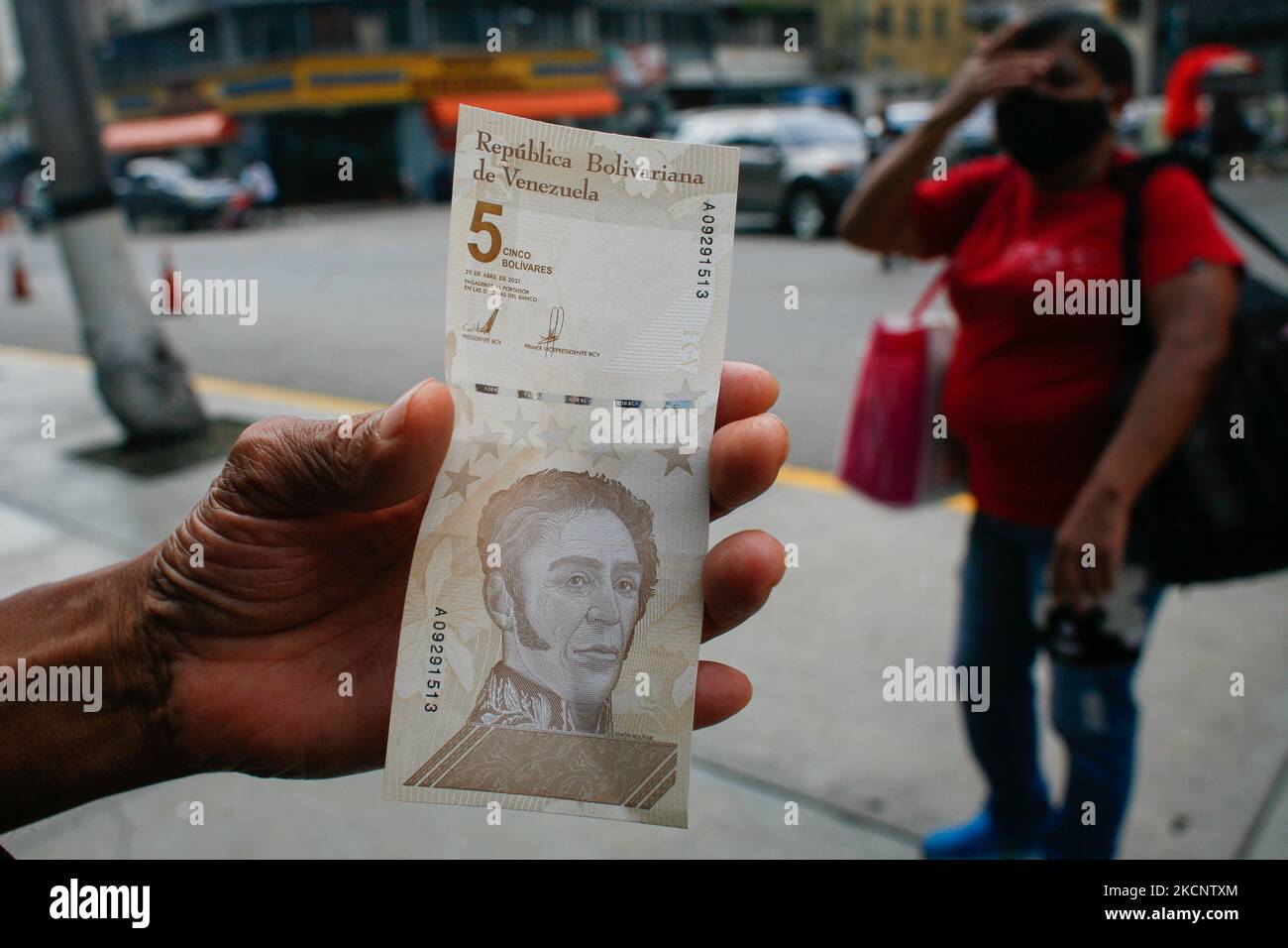A man shows the new 5 bolivar banknote after withdrawing it from an ATM ...