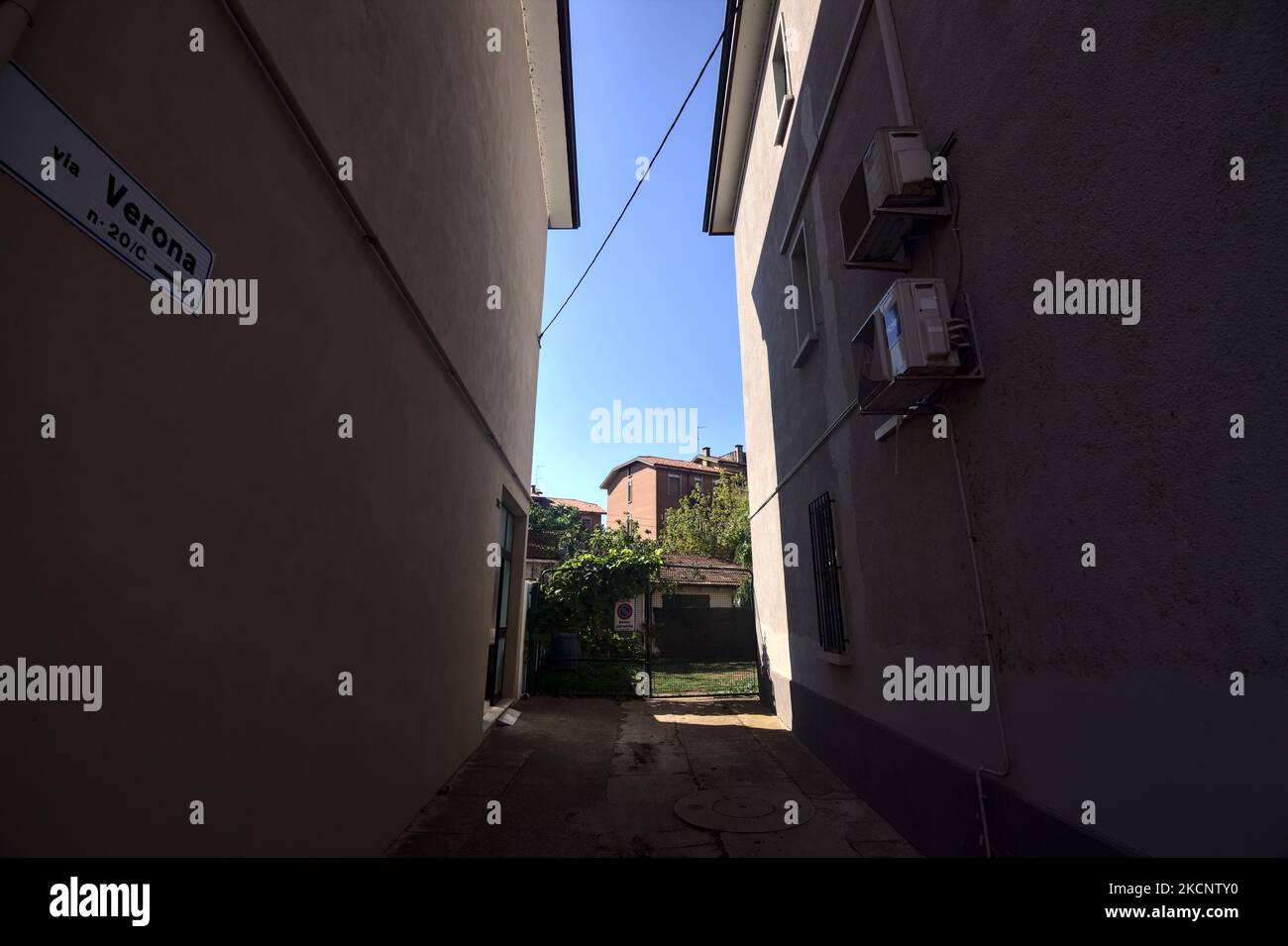 Narrow alley in the shade blocked by a gate Stock Photo - Alamy
