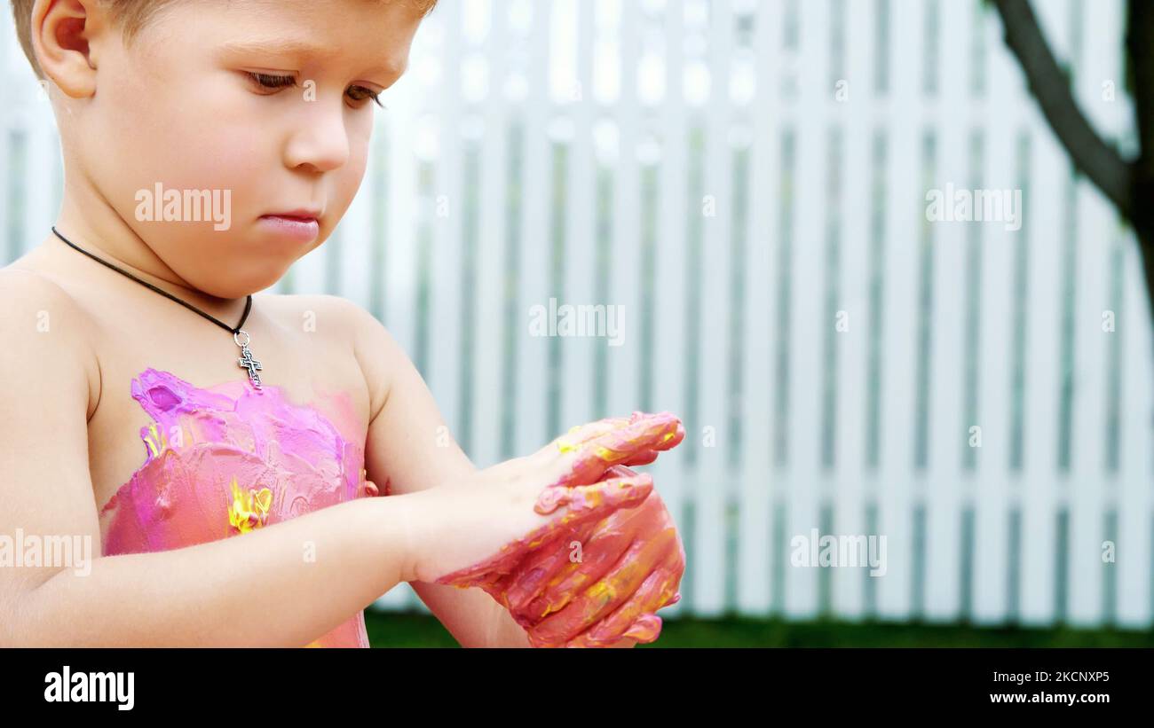 a little child, a four-year-old boy playing, painting with finger ...