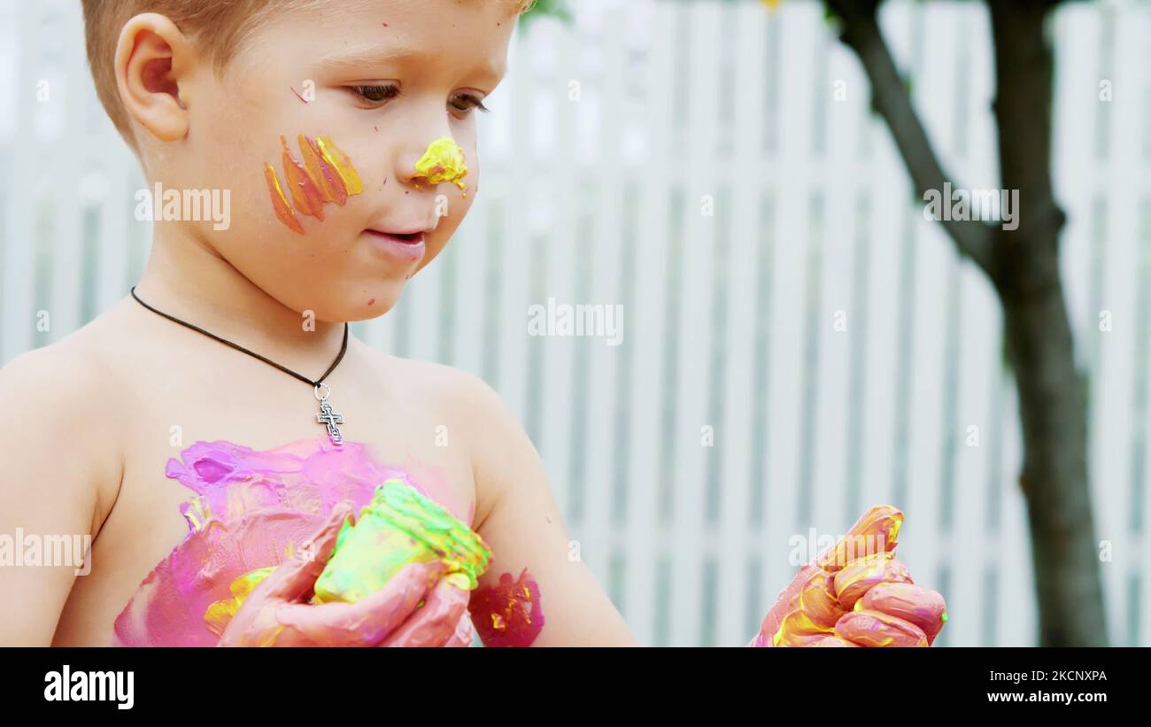 a little child, a four-year-old boy playing, painting with finger ...