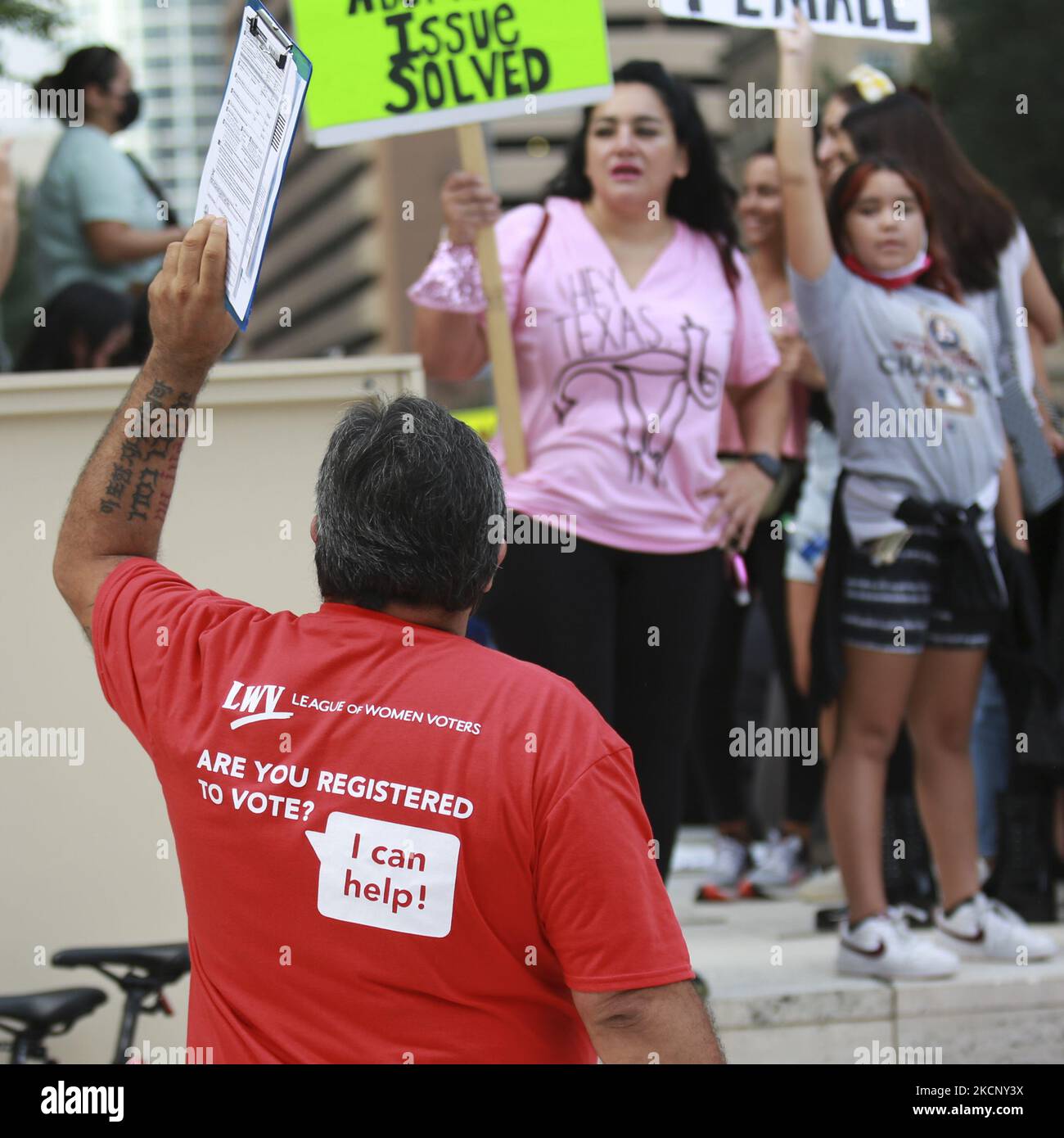 A man helps people register to vote at the Women's March on October 2nd ...