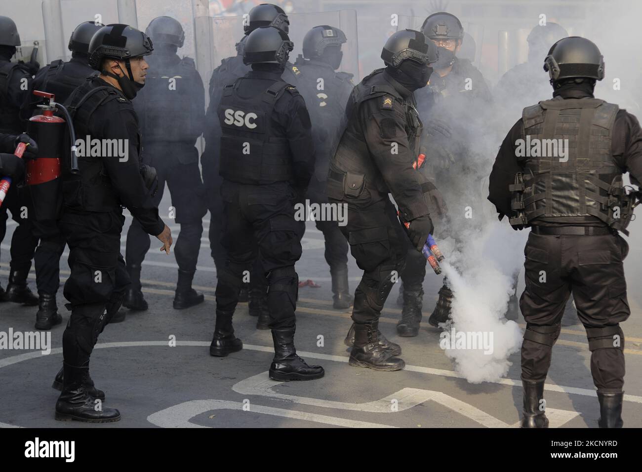 Police officers hold tear gas flares to be thrown on Eje Central in ...