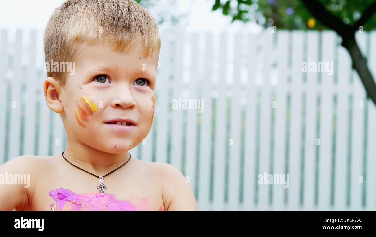 a little child, a four-year-old boy playing, painting with finger ...