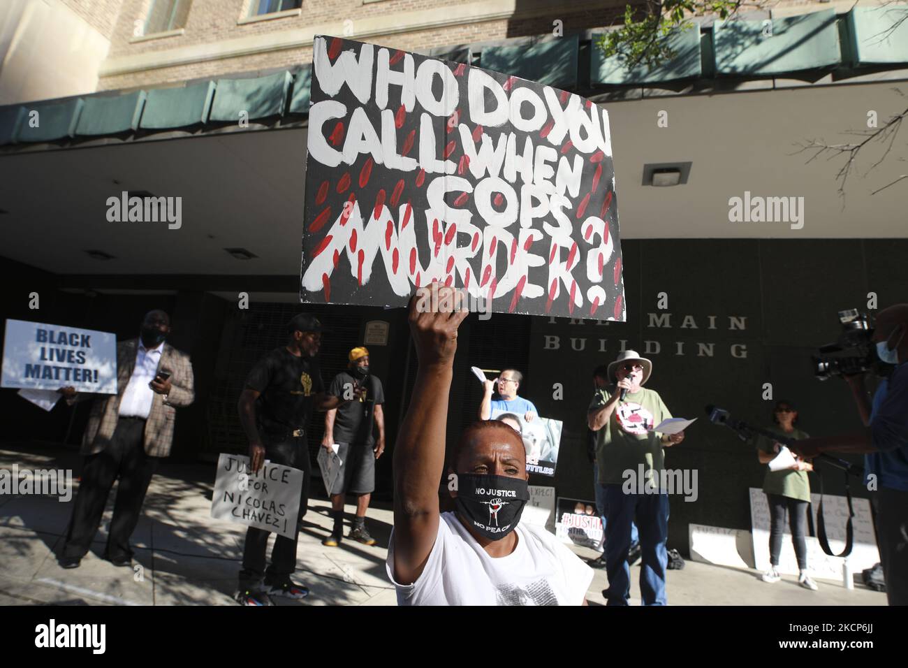 "Who do you call when cops murder?" A woman directs her sign toward the ...