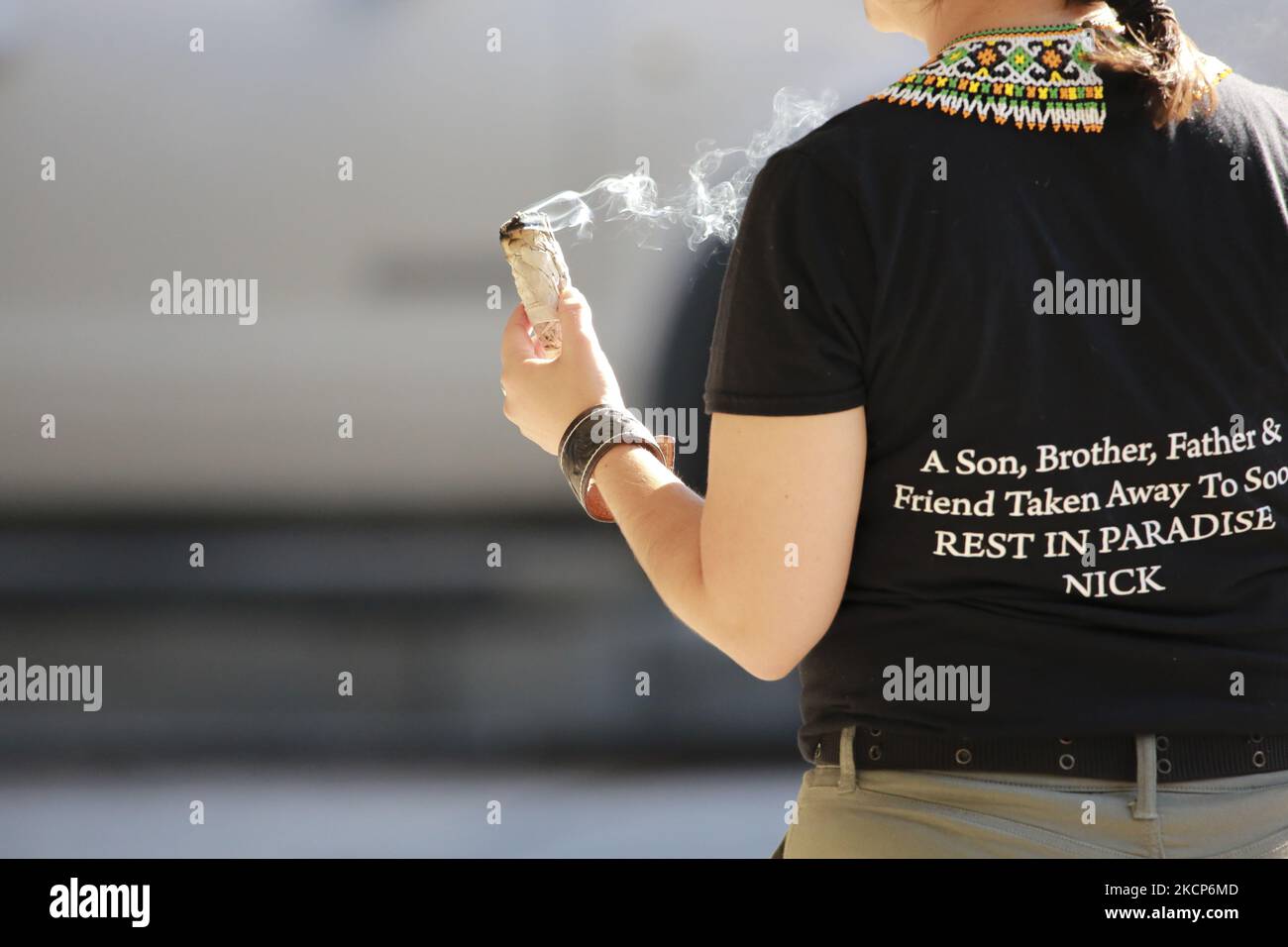 A protestor burns sage and wears a shirt memorializing Nicolas Chavez ...