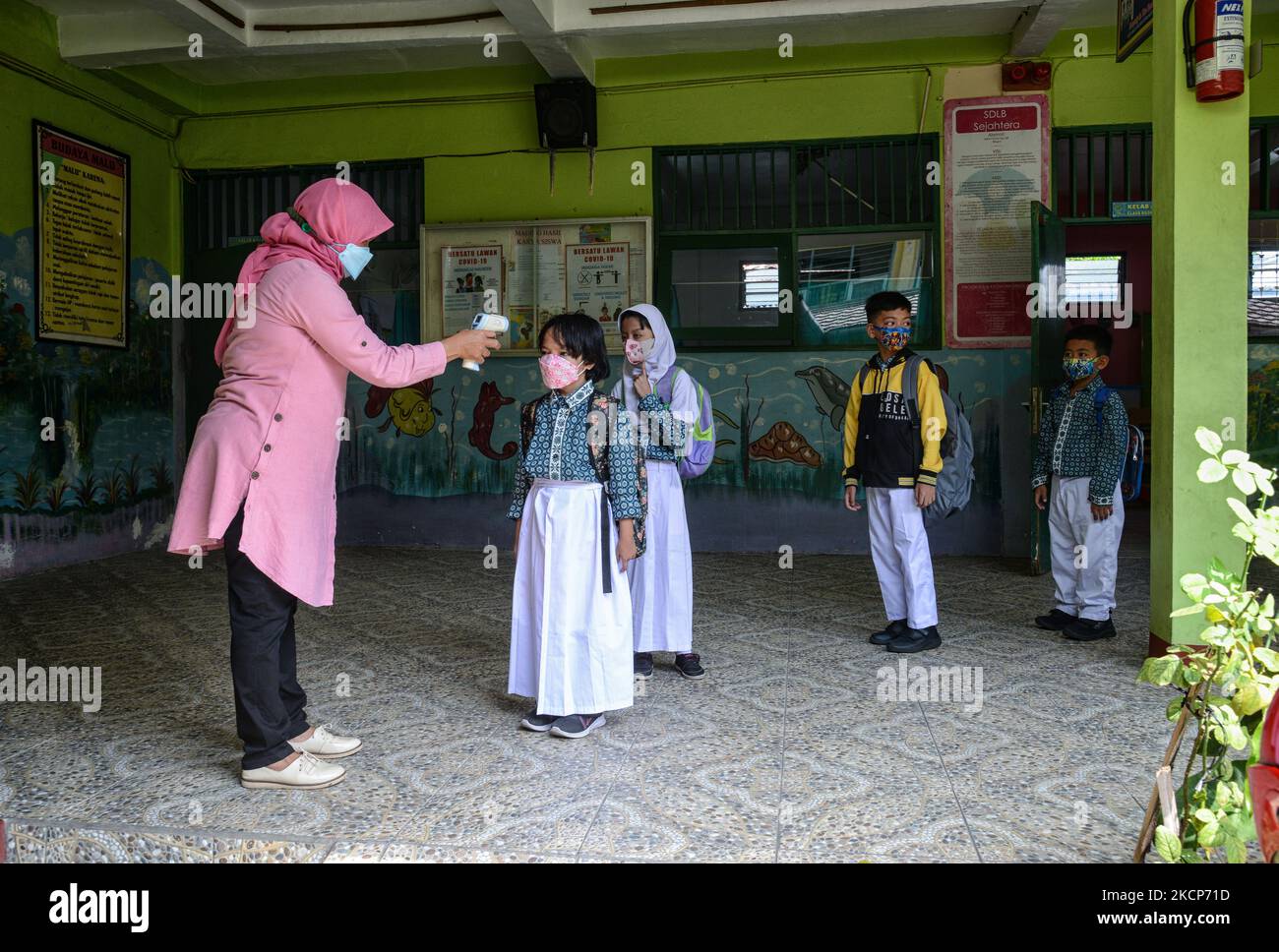 A teacher checks the body temperature of a student disabilities at SLB ...