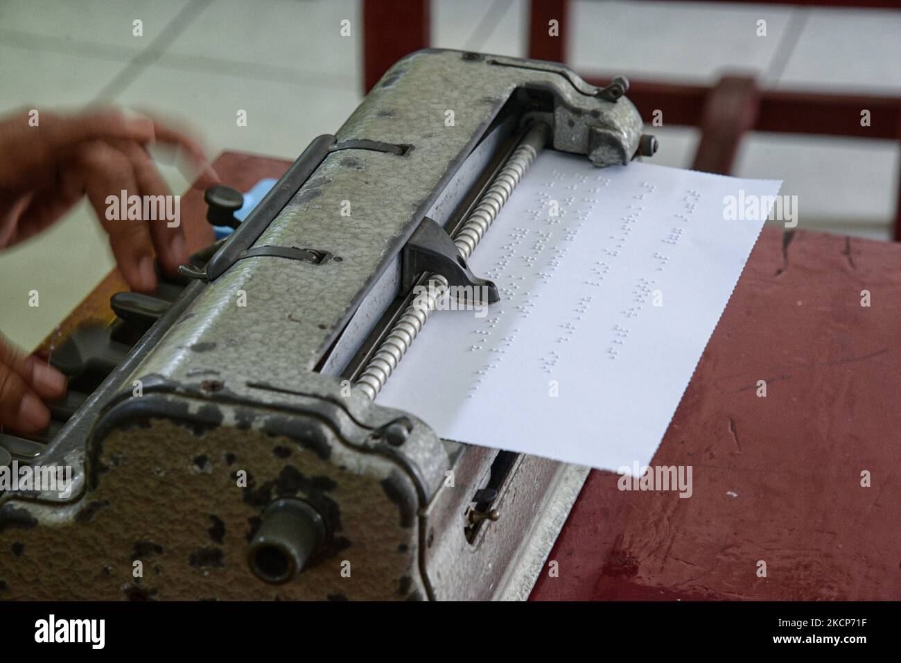 A teacher visually impaired student uses a braille typewriter at SLB ...