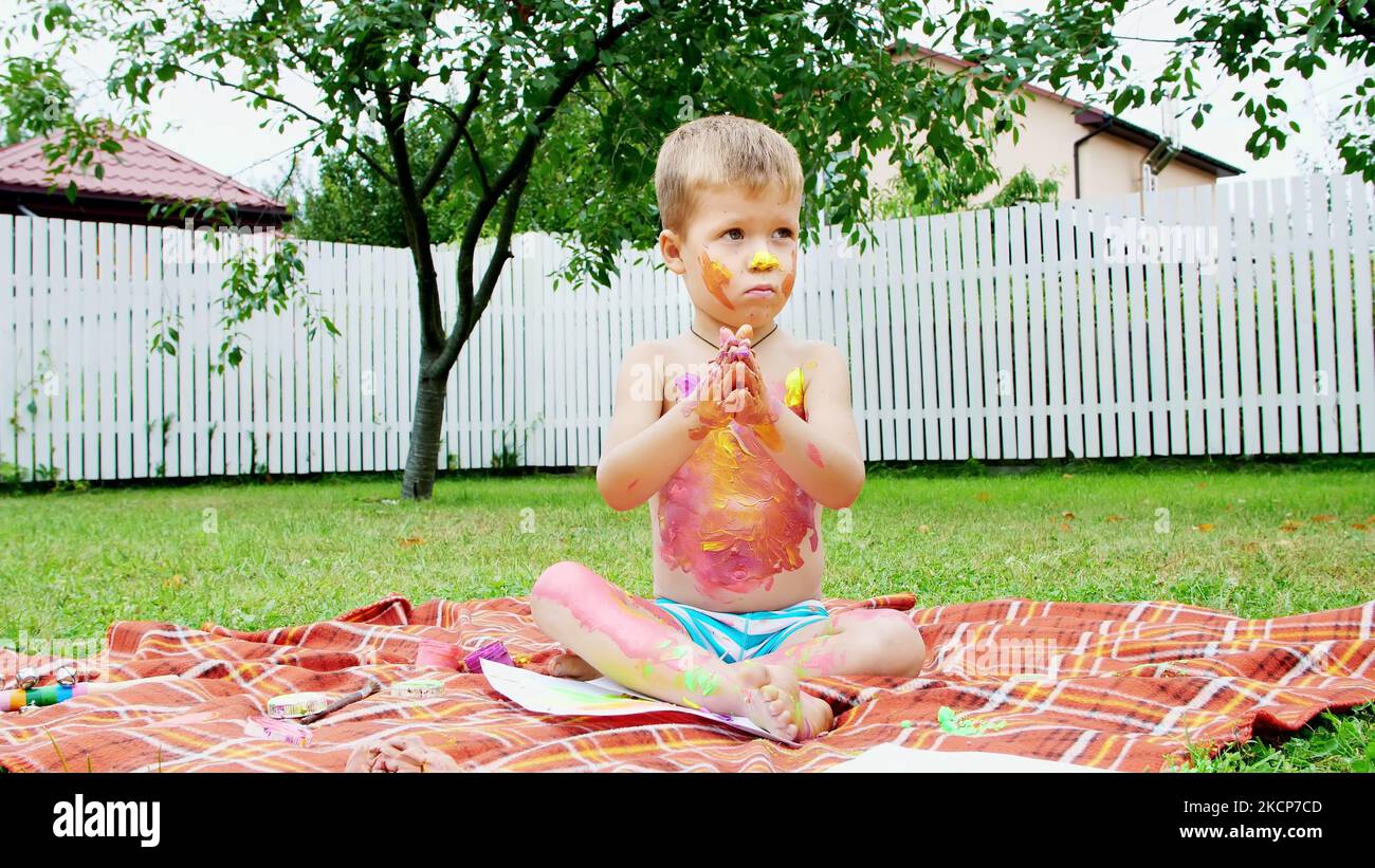 a little child, a four-year-old boy playing, painting with finger ...
