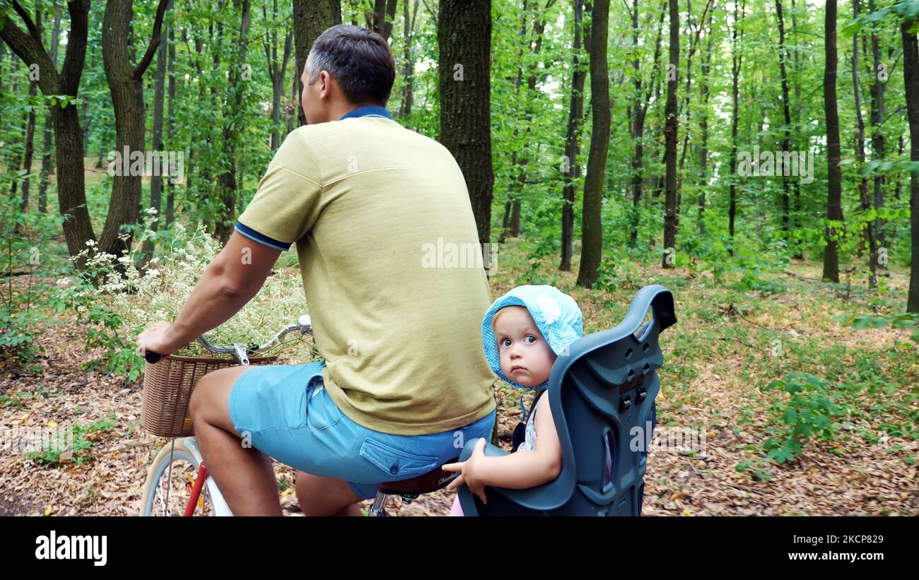 a man with a child riding a bicycle in the forest, in the summer, the ...
