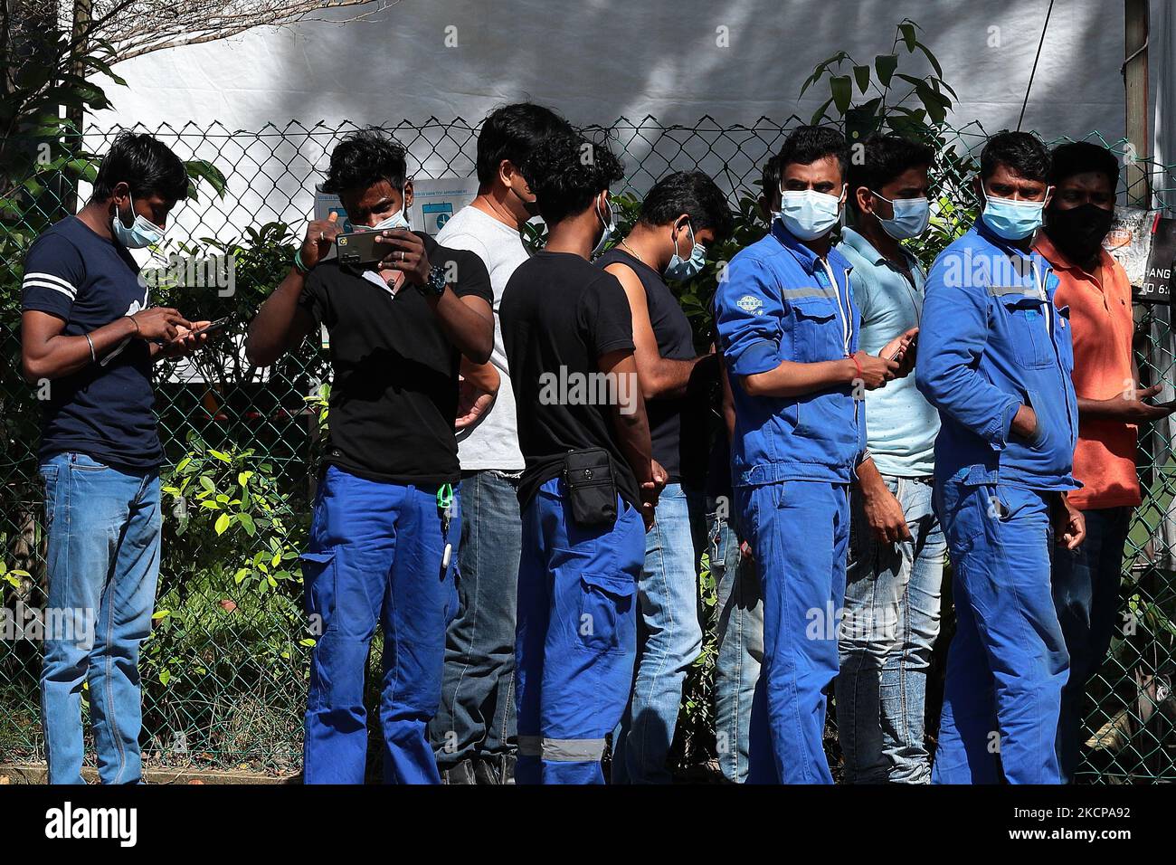 Migrant workers wait in queue to enter a Regional Screening Centre to ...