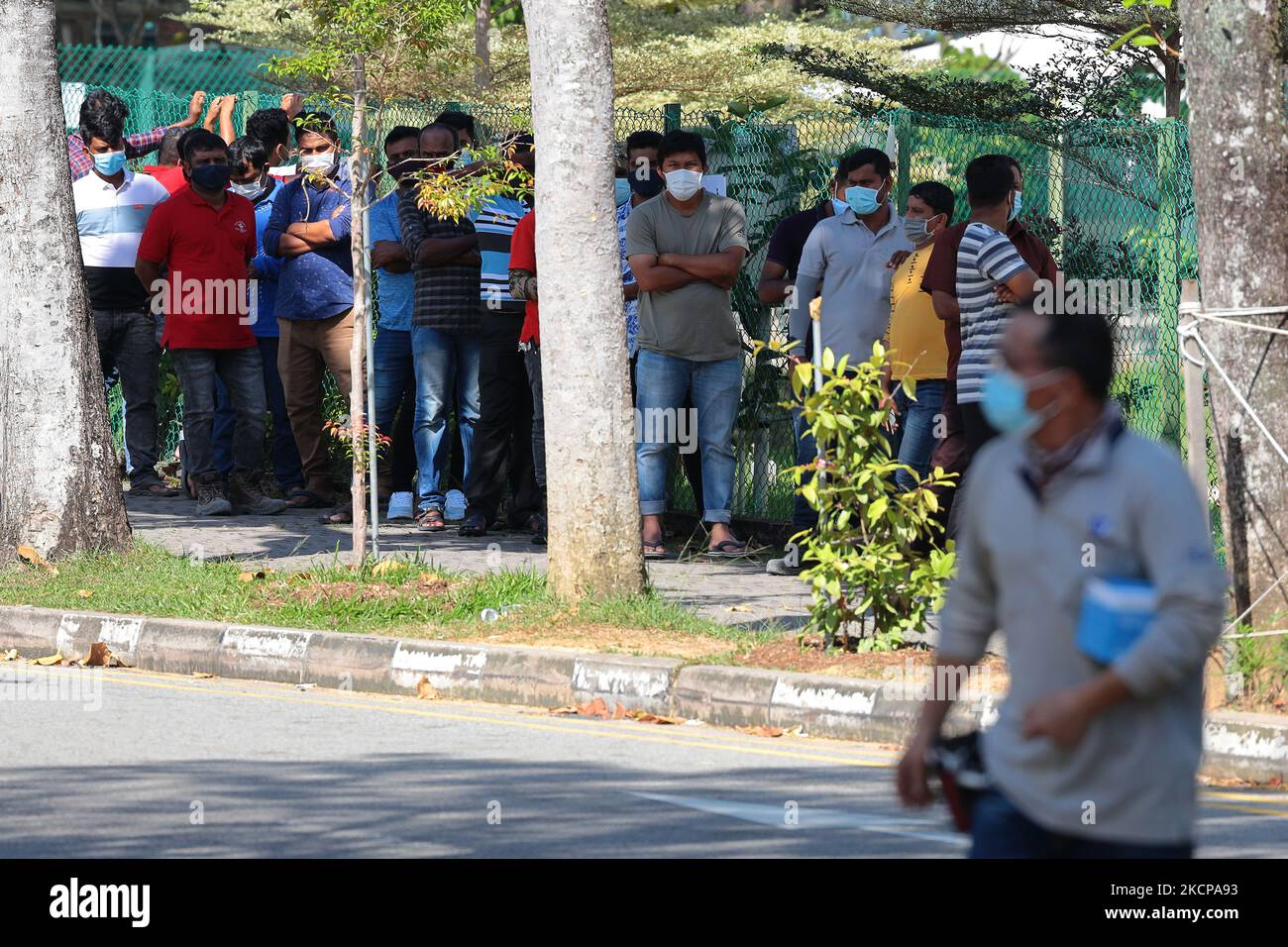 Migrant workers wait in queue to enter a Regional Screening Centre to ...